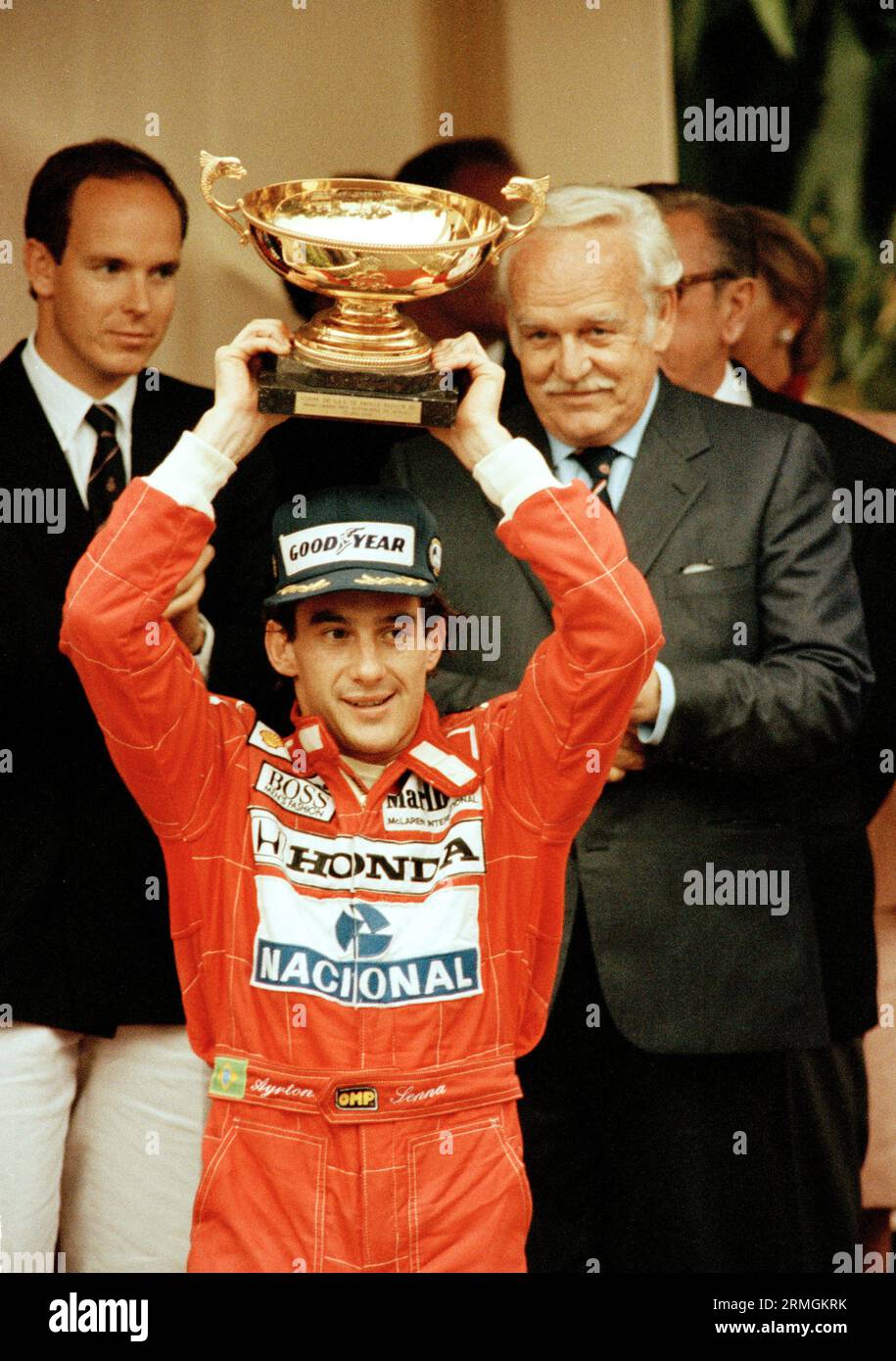 Ayrton Senna of Brazil, center, proudly holds the winner's cup aloft ...
