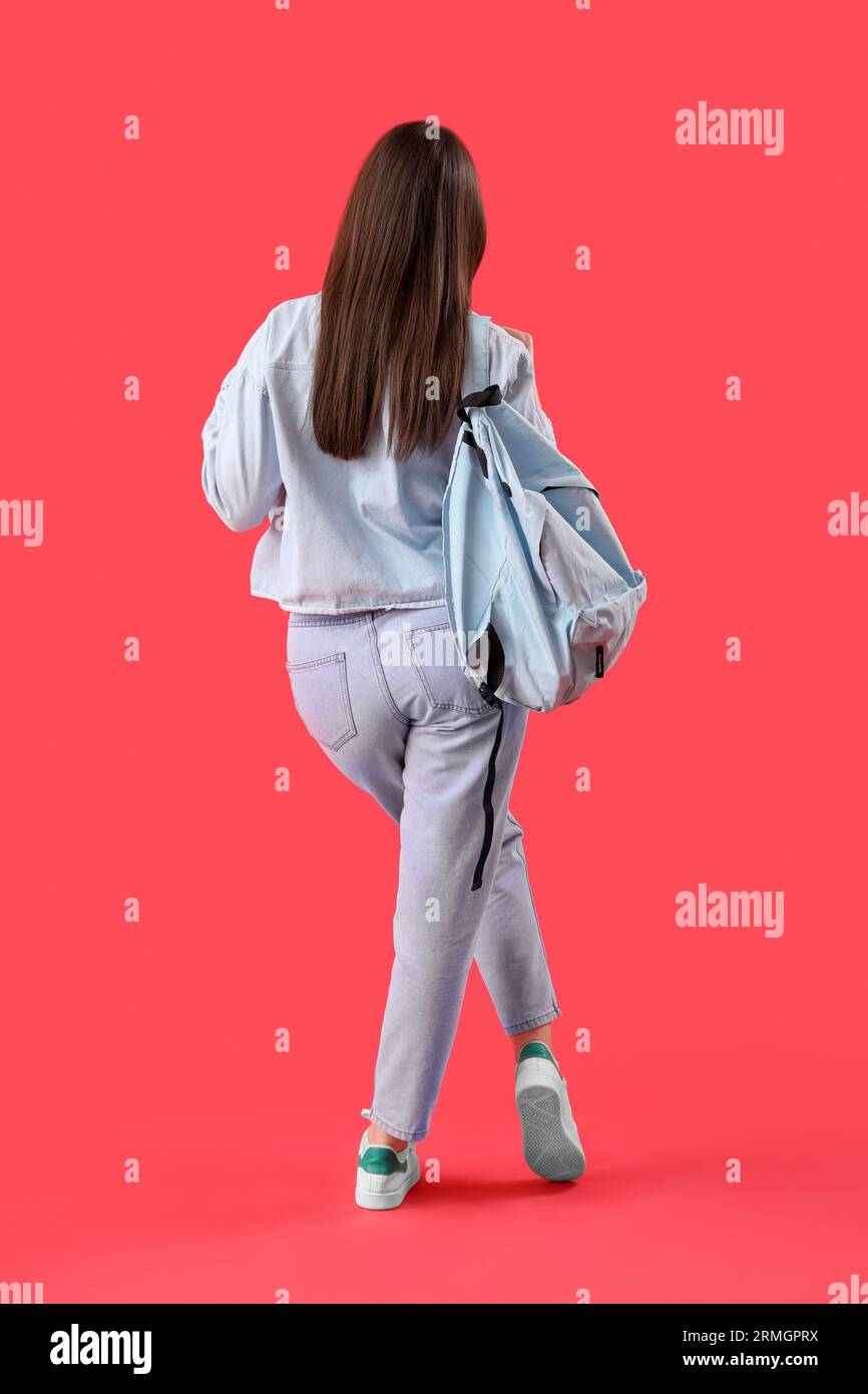 Female student with backpack on red background, back view Stock Photo ...