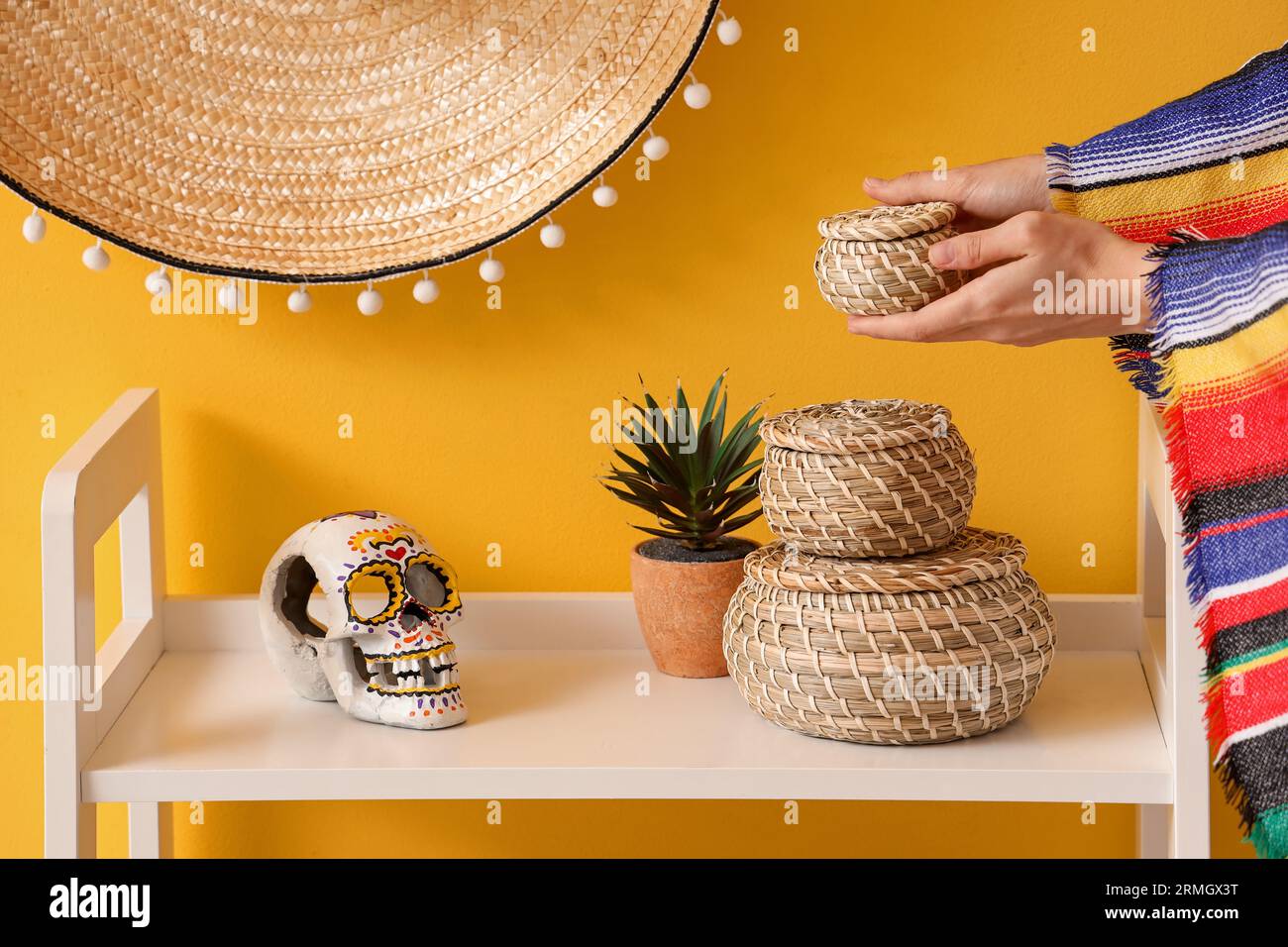 Woman in poncho putting wicker baskets on white shelving unit with ...