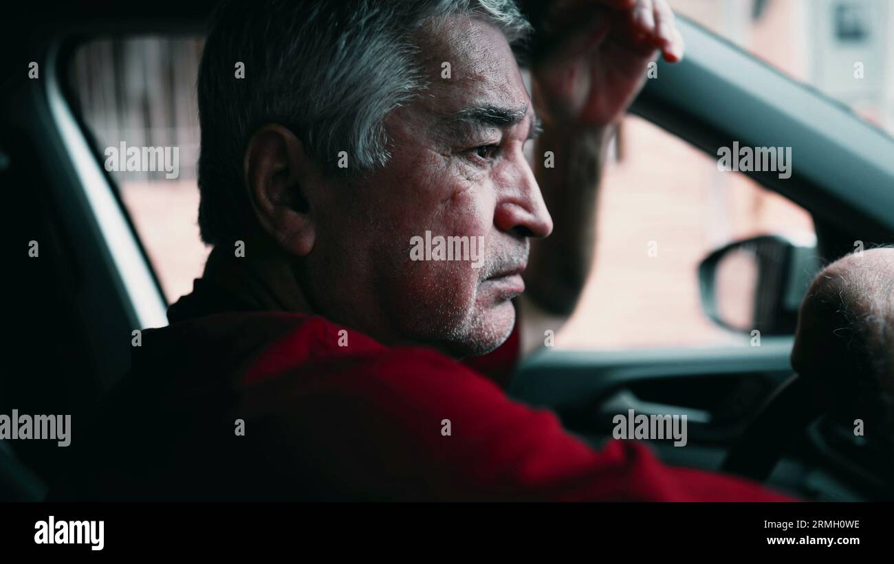 Elderly man suffering emotional pain inside car, parked in street ...
