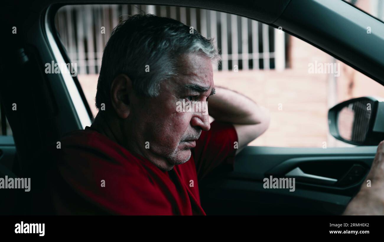 Elderly man suffering emotional pain inside car, parked in street ...