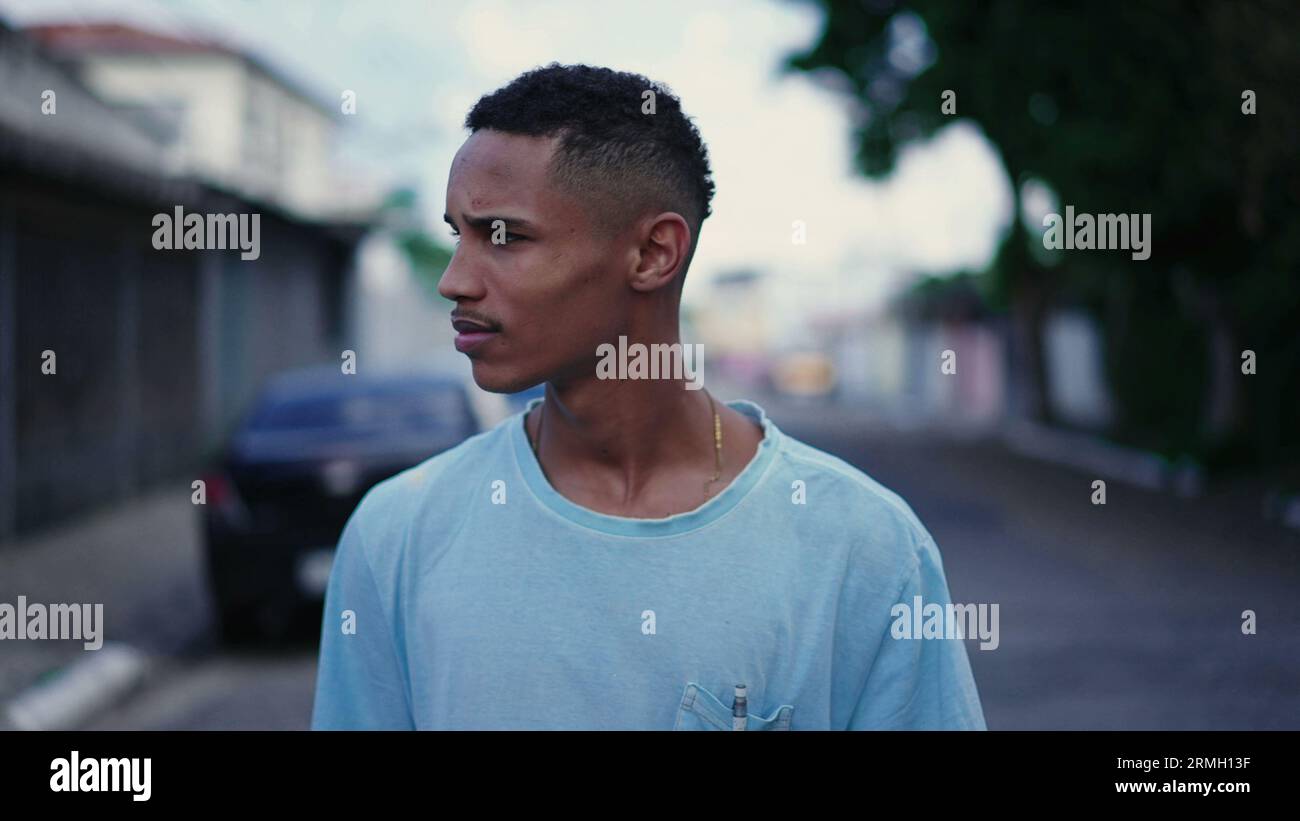 One confident young black man walking forward in street. Close-up face ...