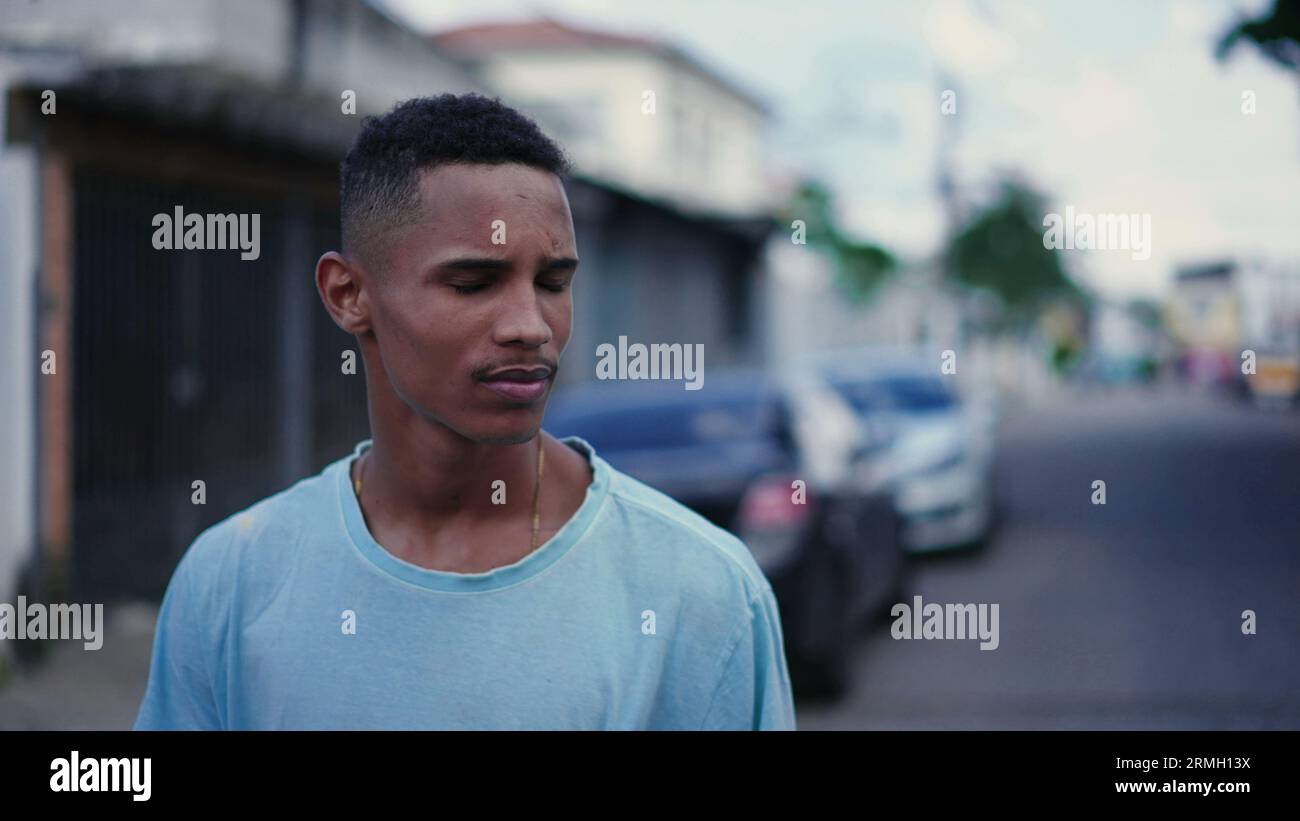 One confident young black man walking forward in street. Close-up face ...