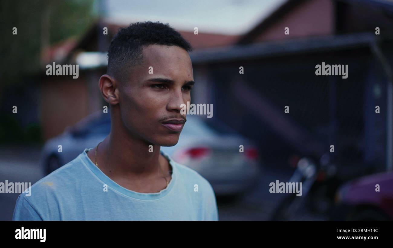One confident young black man walking forward in street. Close-up face ...