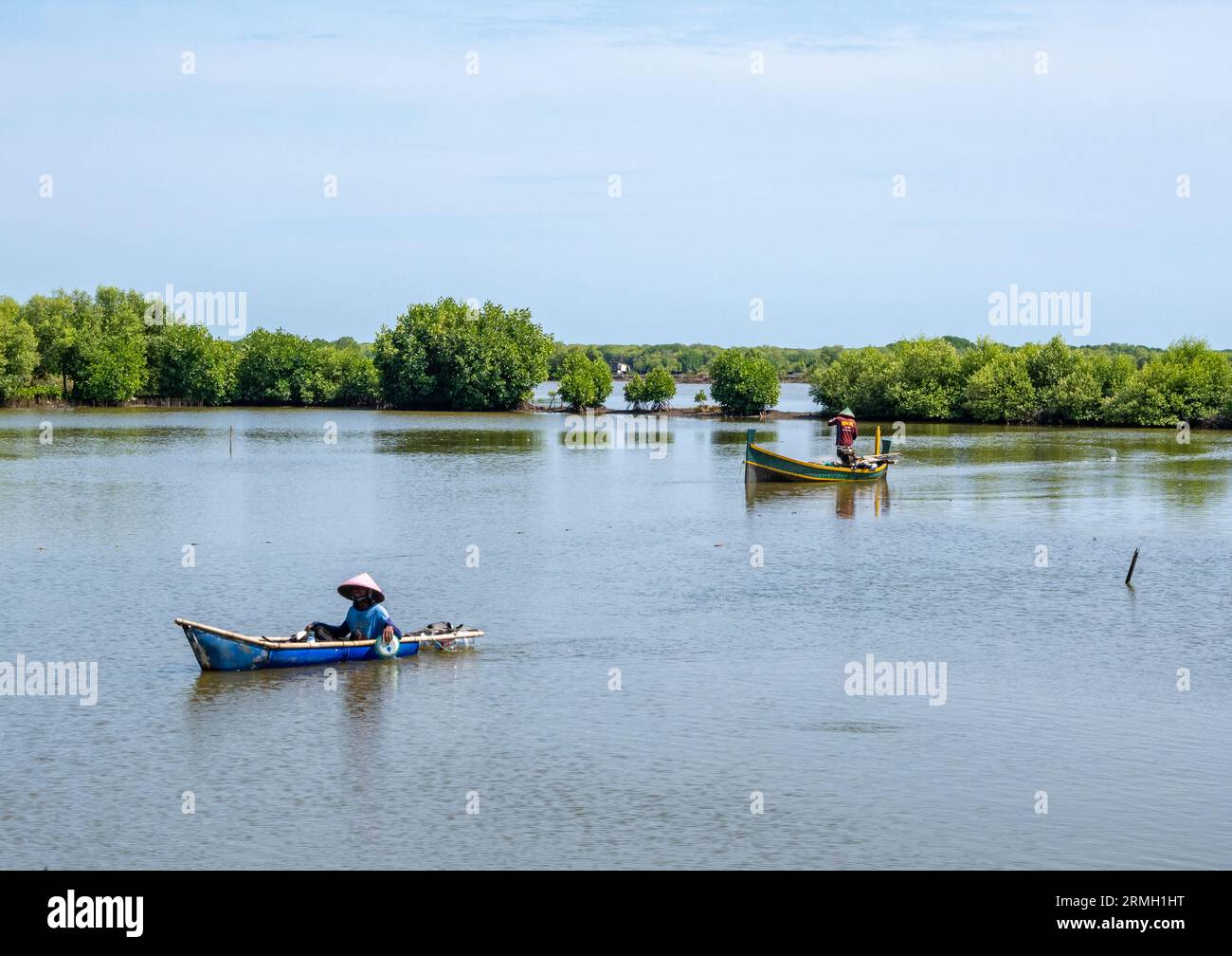 Fishermen in small boats fishing in coastal water with mangrove trees ...