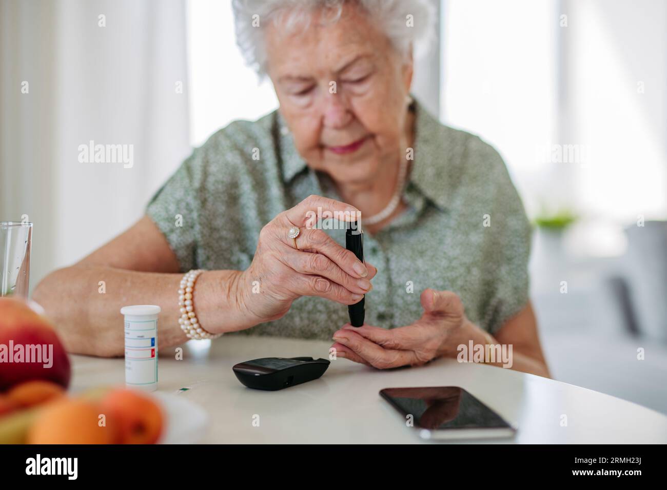 Close up of diabetic senior patient checking her blood sugar level with ...
