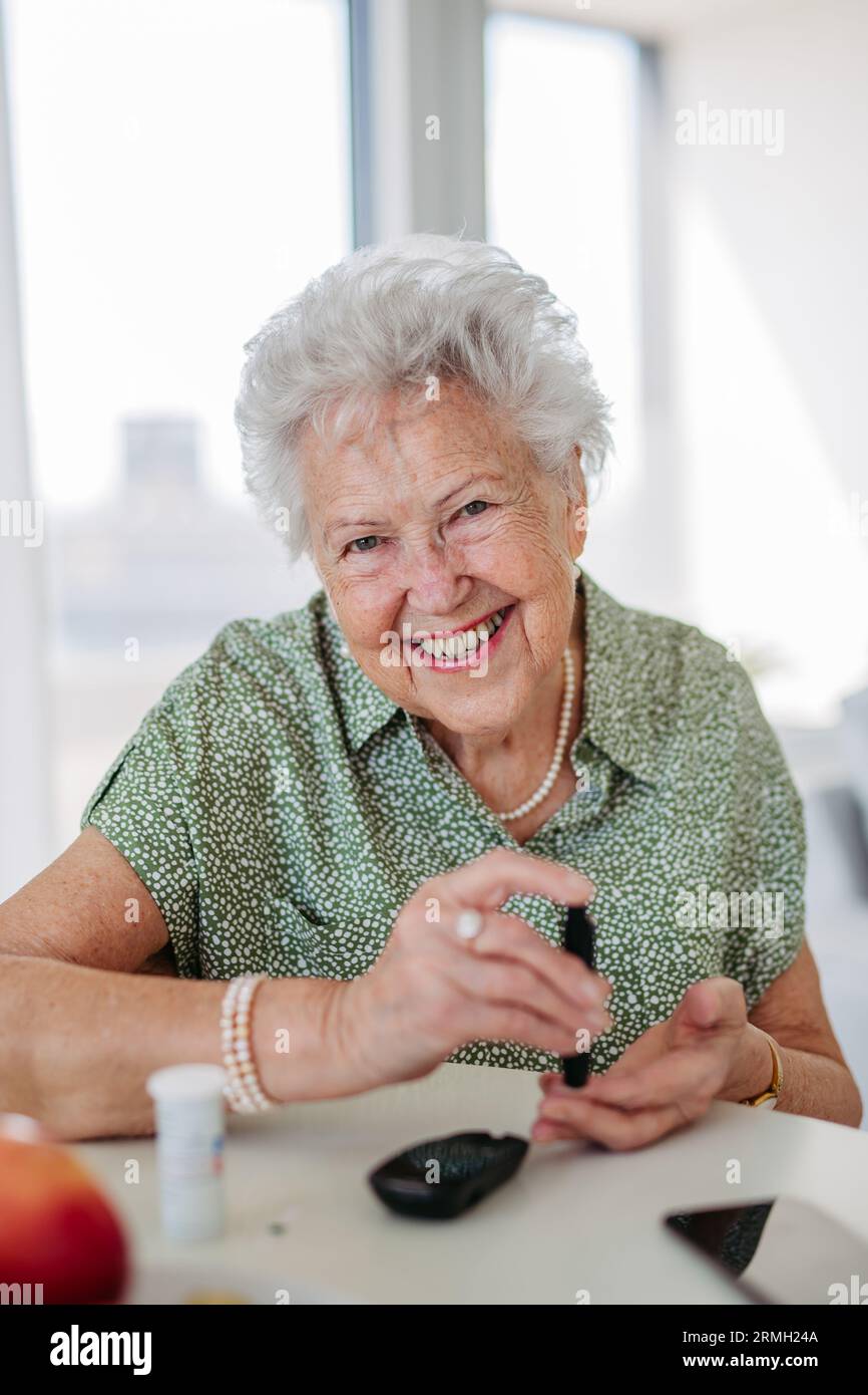 Portrait of diabetic senior patient checking her blood sugar level with ...