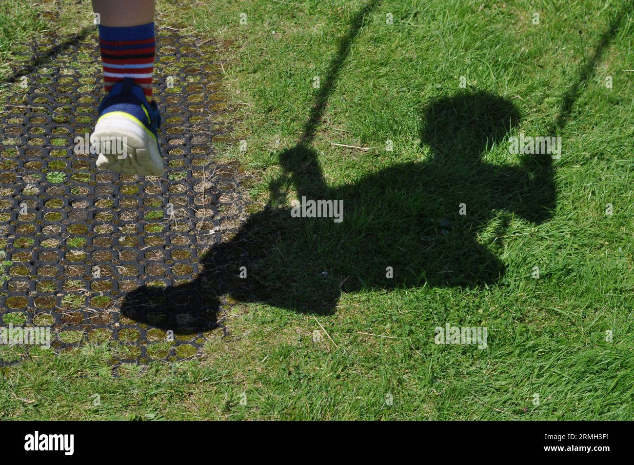 Shadow of a young child swinging on a swing Stock Photo - Alamy