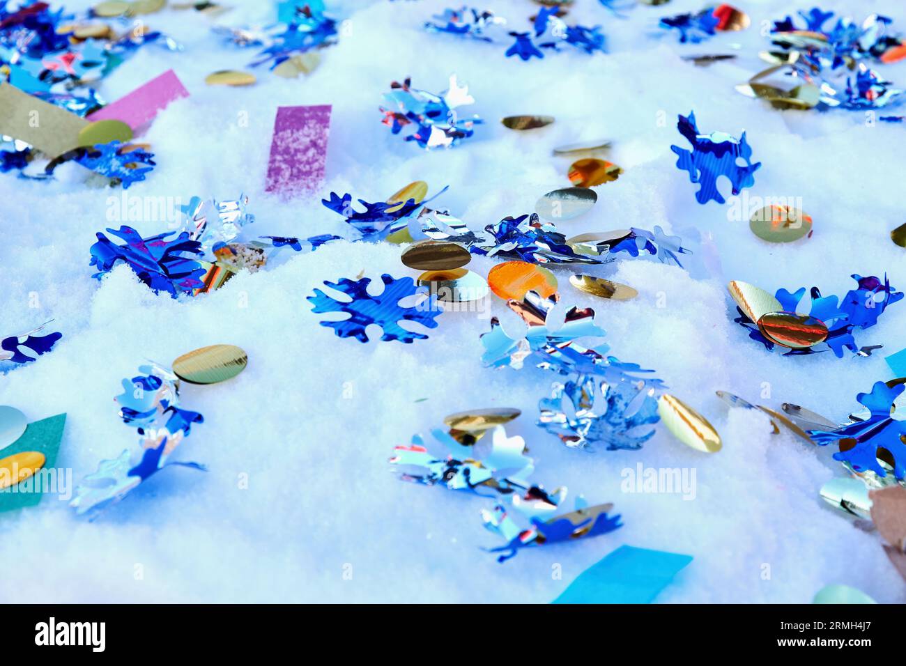 Ornate confetti and ribbons from a cracker is scattered on fresh snow ...
