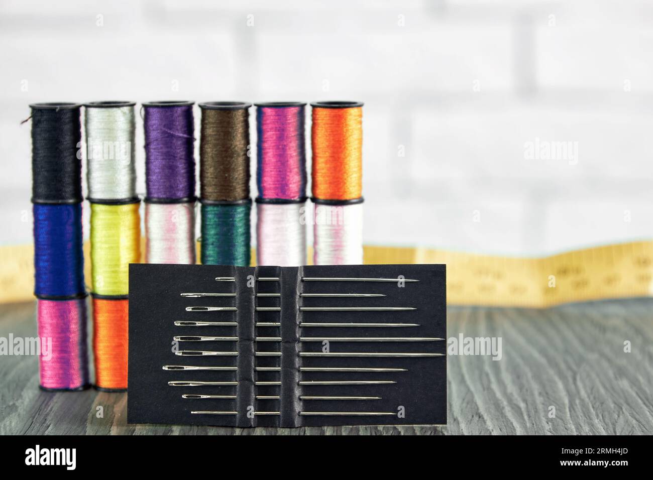 Seamstress set of multiple needles and colorful threads on the wooden ...