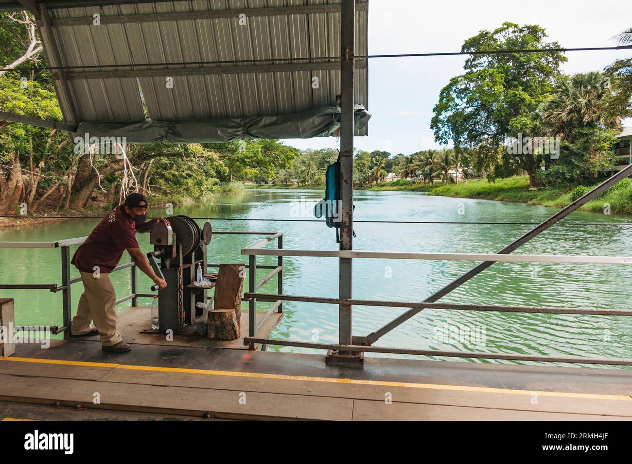a hand-wound car ferry takes vehicles across the Mopan River at ...