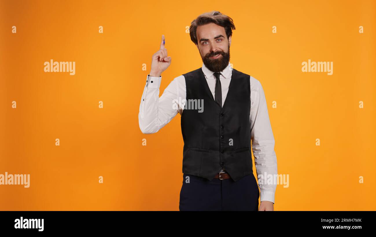 Elegant butler points up on camera, showing something above head while ...