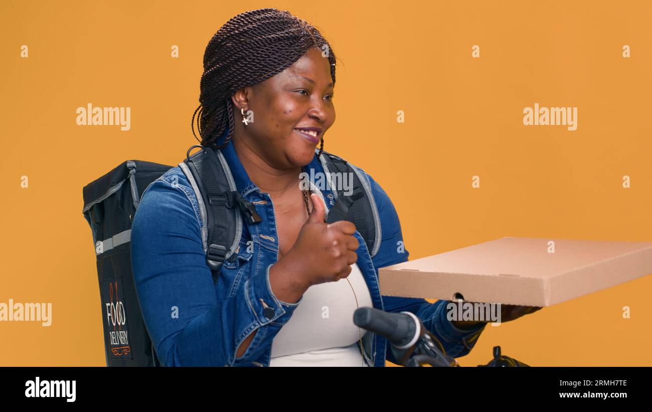 Black woman on bicycle brings package from restaurant for timely and ...