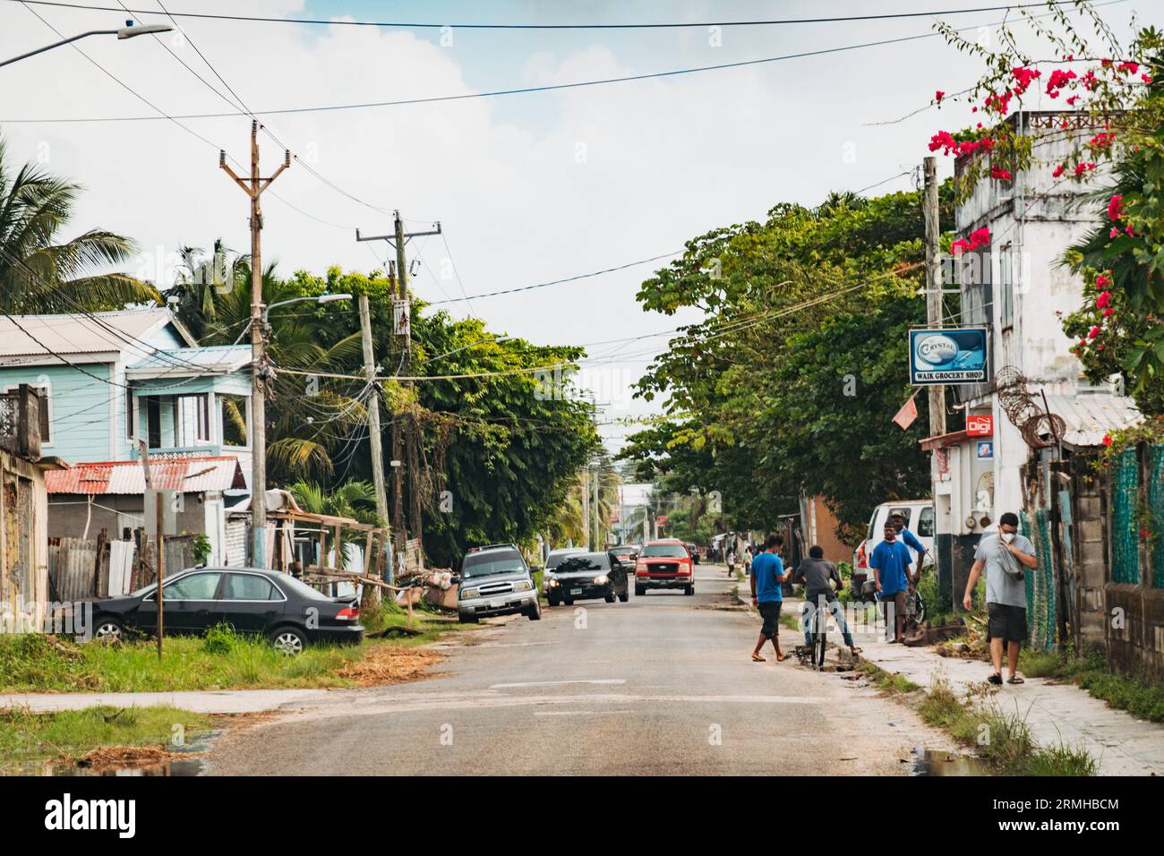a group of men stand on the sidewalk near a grocery shop on a street in ...