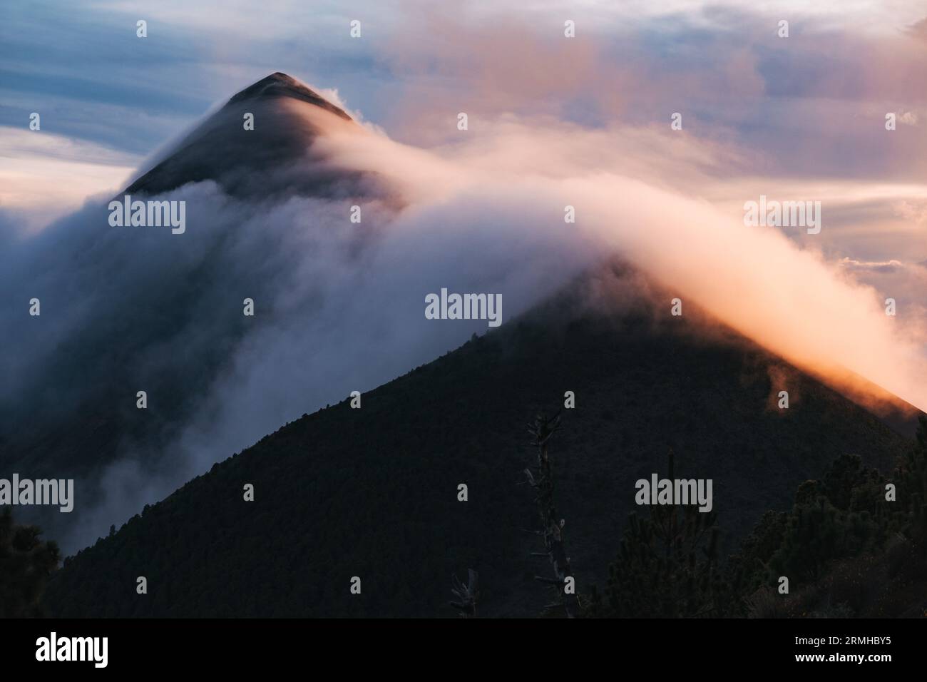 cloud wisps over the top of Fuego Volcano in Guatemala, creating a ...