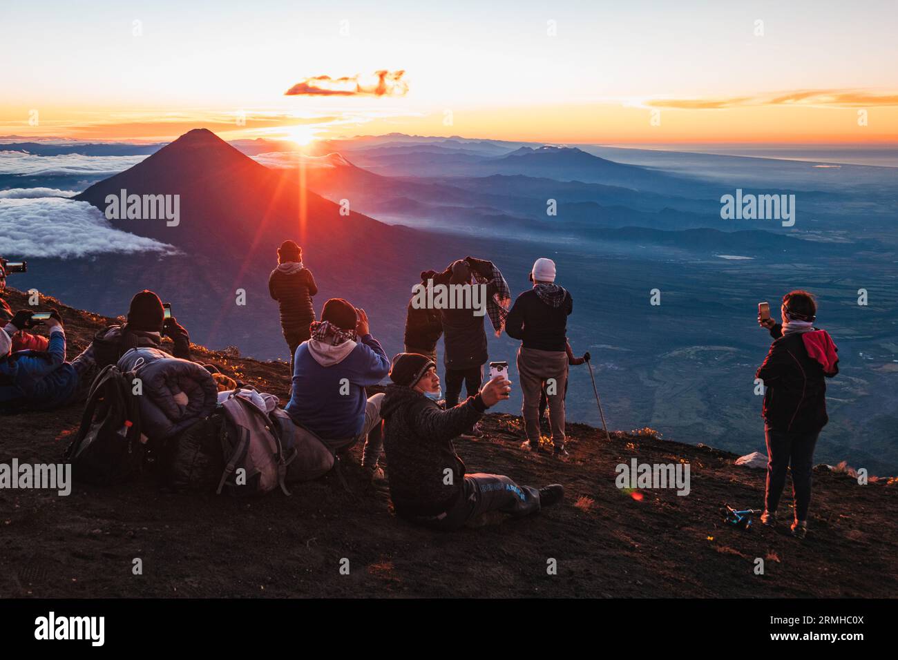 Tourists watch sunrise over Agua Volcano, from atop Acatenango Volcano ...