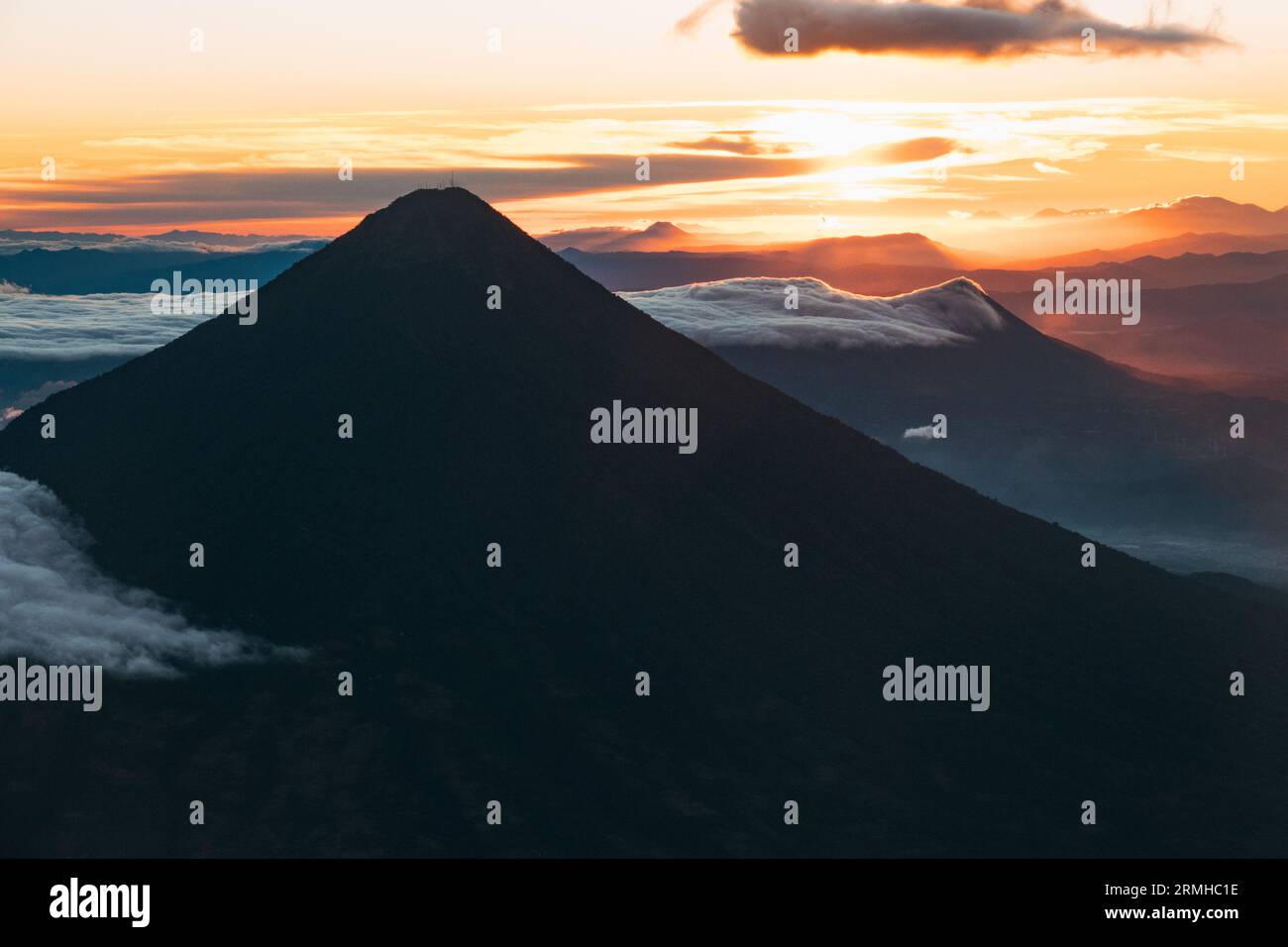 The sun rises from behind Agua Volcano in Guatemala, casting a dramatic ...