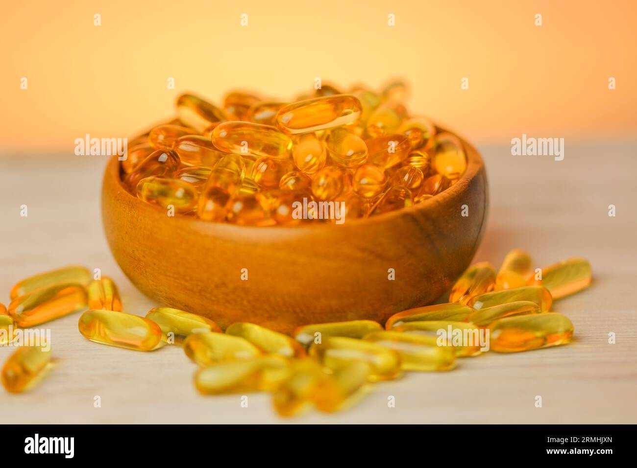 Fish oil capsules in a cup on a blurred orange background.Omega fatty ...