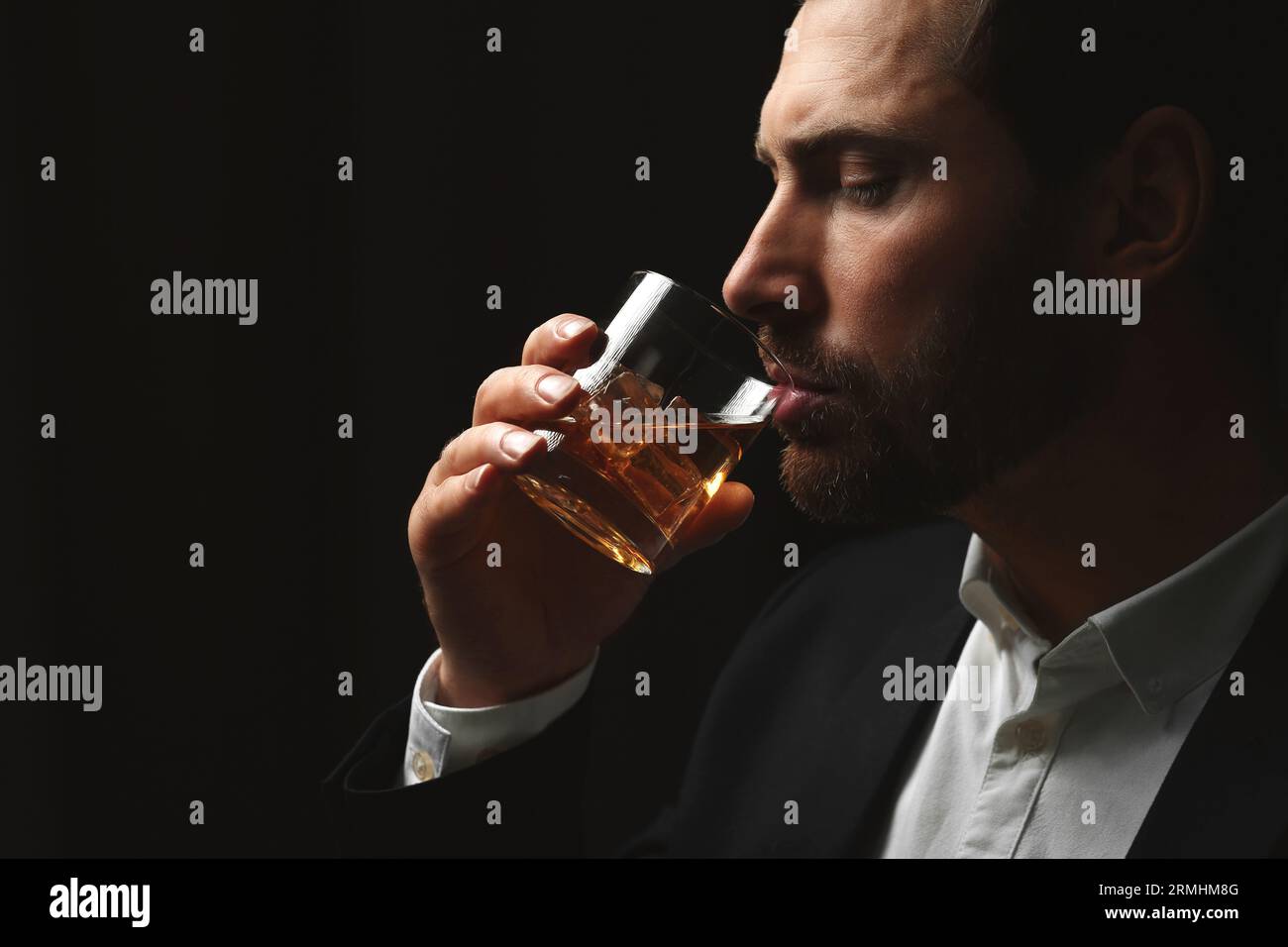 Man in suit drinking whiskey on black background Stock Photo - Alamy
