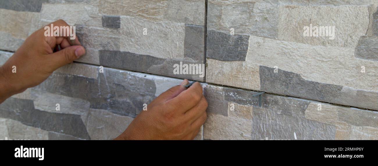 Image of the hands of a tiler mason inserting shims into freshly laid ...