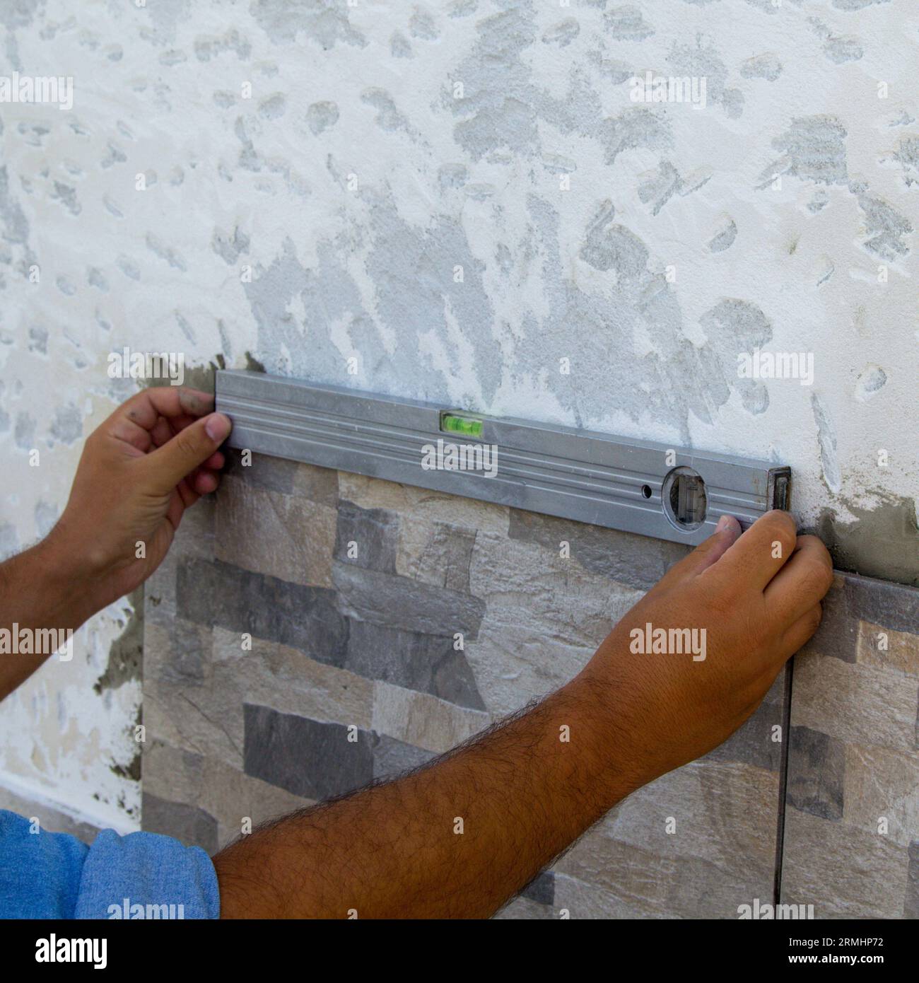 Image of the hands of a tiler while he checks the accuracy of the newly ...