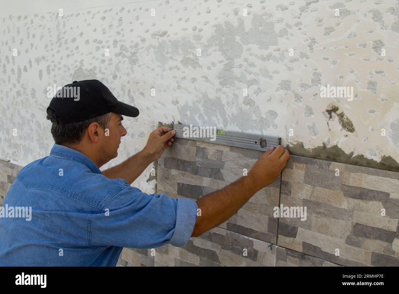 Image of a tiler who uses a spirit level to check and ensure that the ...