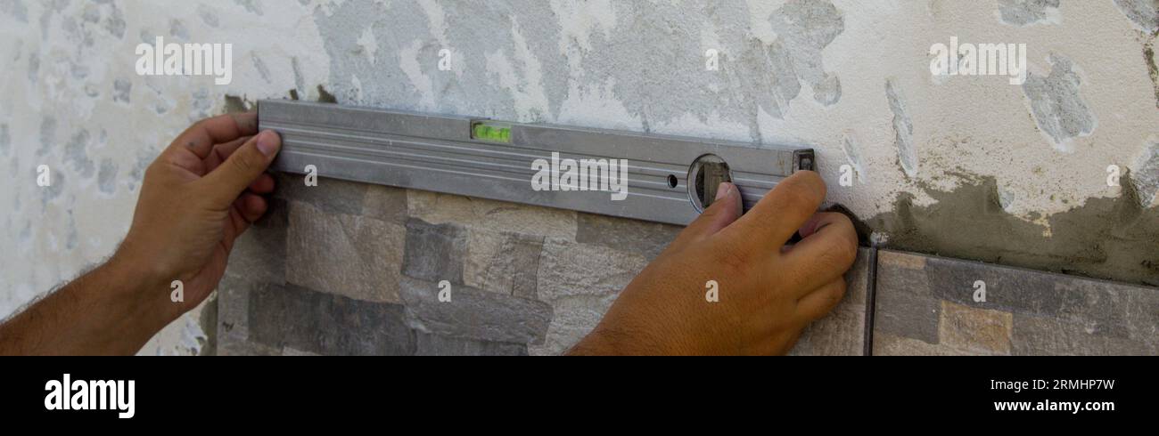 Image of the hands of a tiler while he checks the accuracy of the newly ...