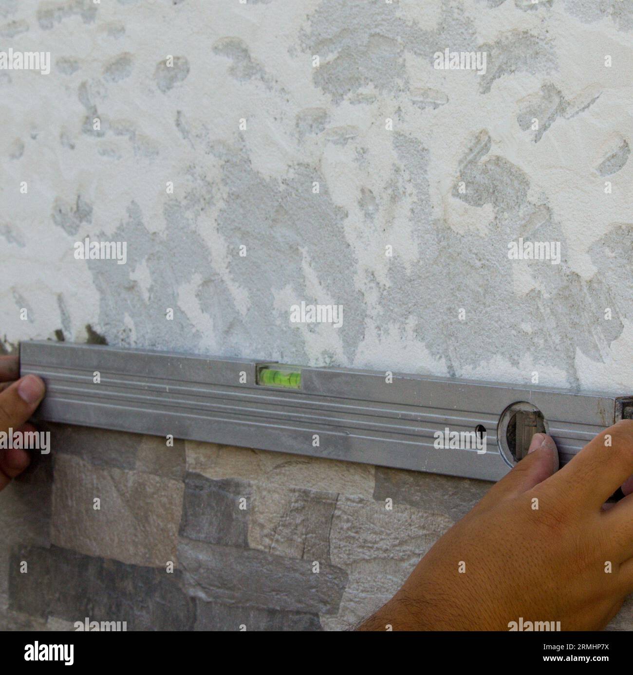 Image of the hands of a tiler while he checks the accuracy of the newly ...