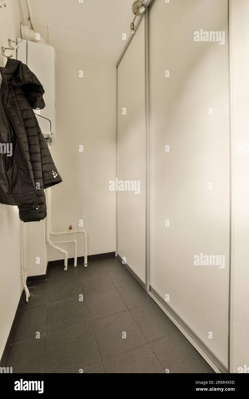 a coat hanging on a wall in a room with white walls and black tile ...