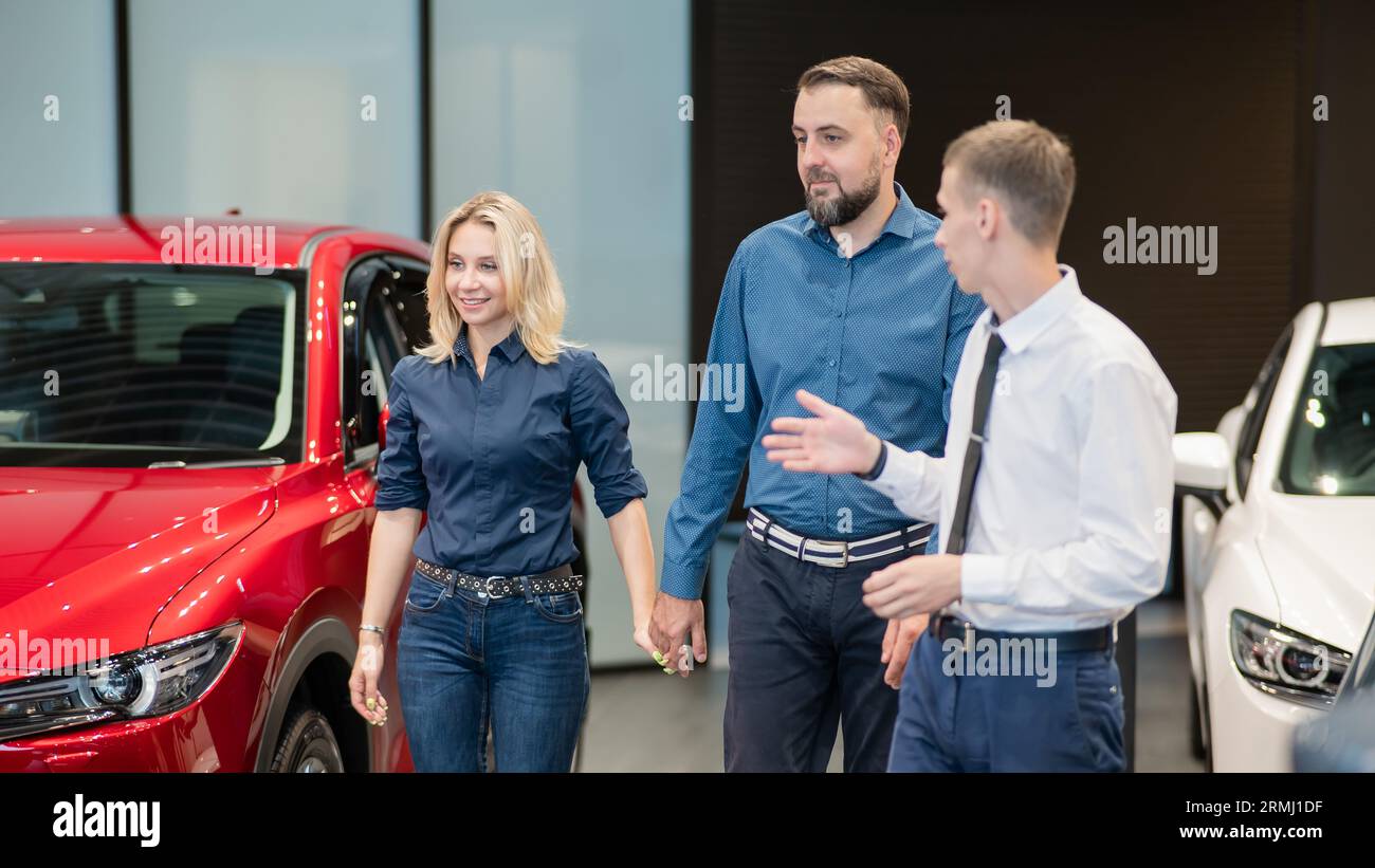 The seller helps a caucasian couple to choose a car Stock Photo - Alamy