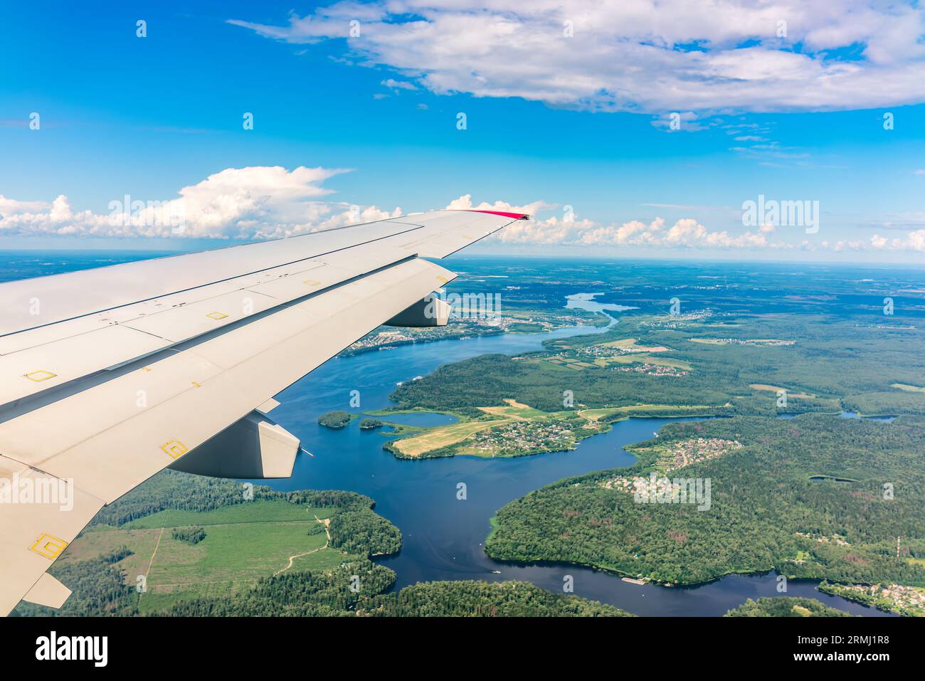 View of airplane wing, blue skies and green land during landing ...