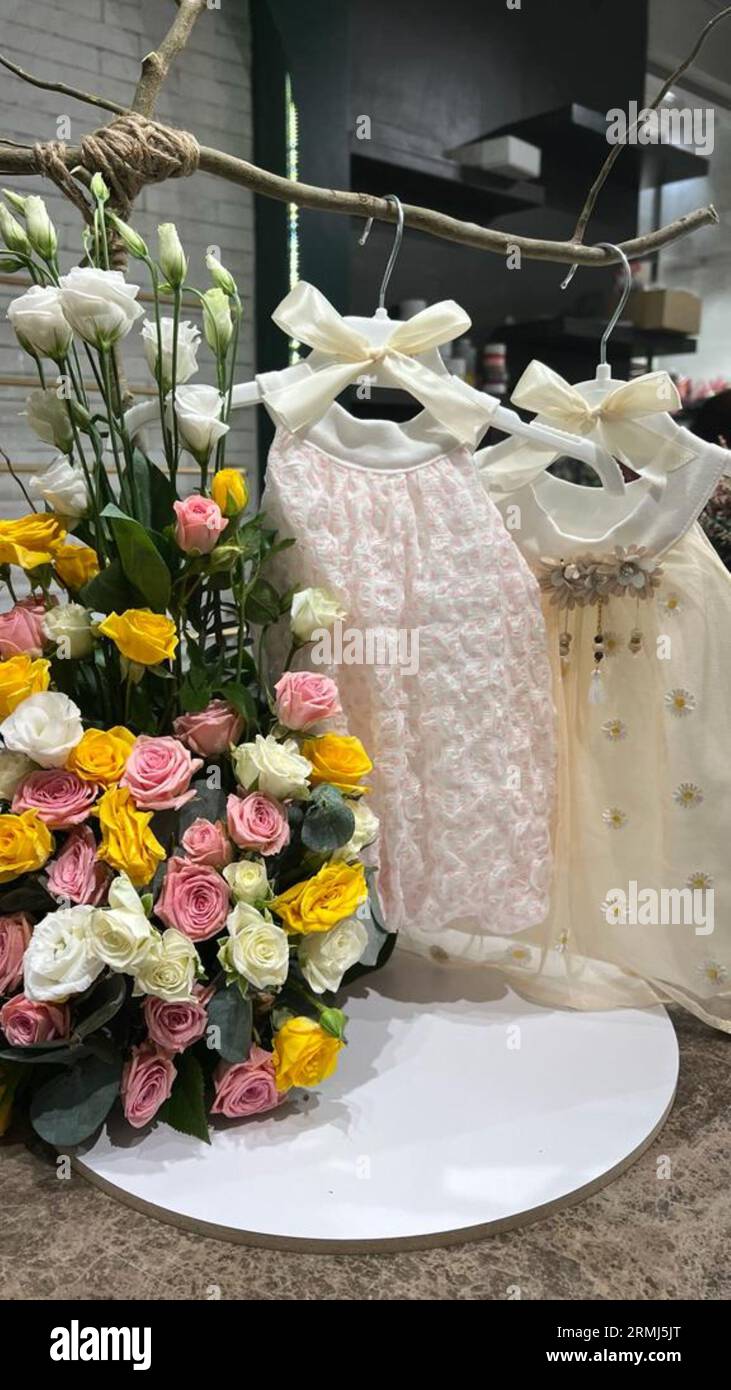 A display of colorful flower arrangements next to a clothing rack with ...