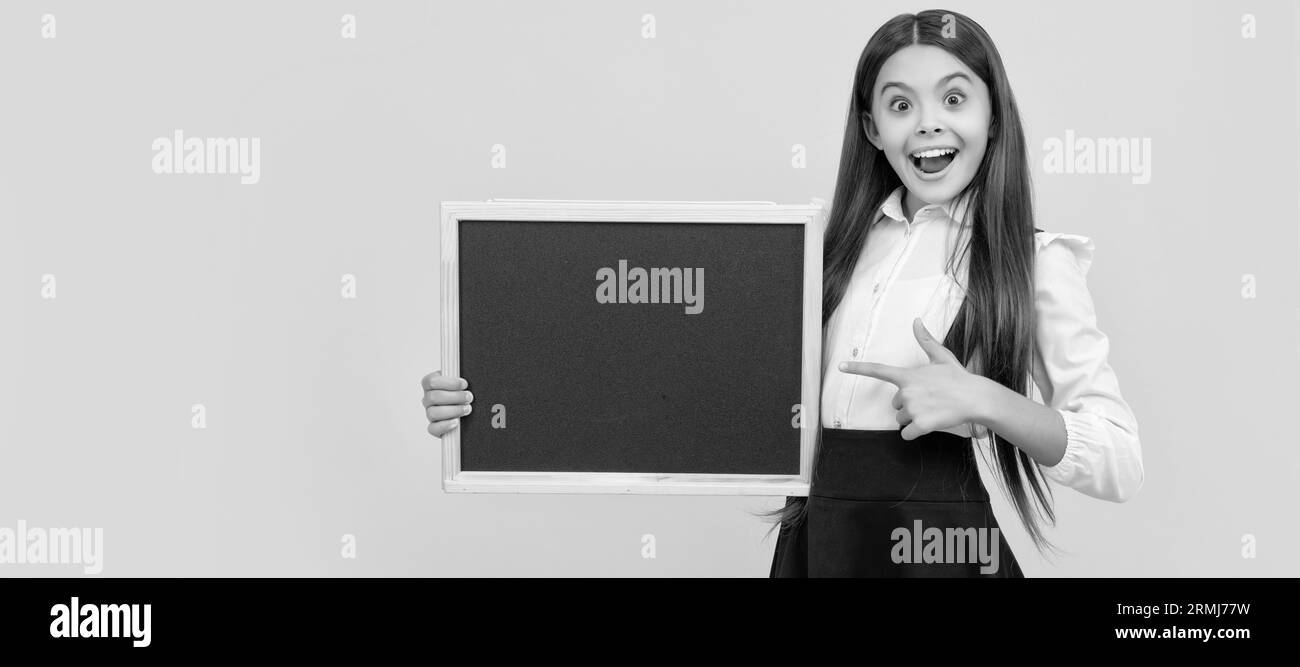 surprised child in uniform pointing finger on school blackboard for ...