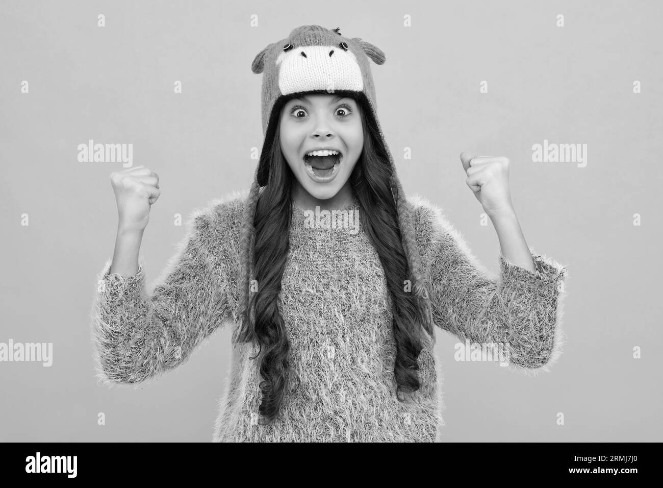 Modern teen girl wearing sweater and knitted hat on isolated yellow ...