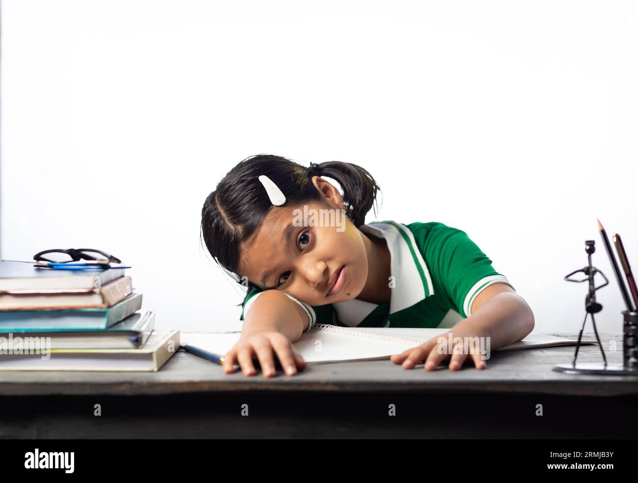 A pretty beautiful Indian schoolgirl child lying exhausted on study ...