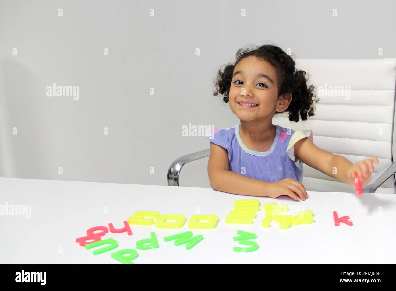 3-year-old brunette Latina girl plays with toy letters and numbers to ...
