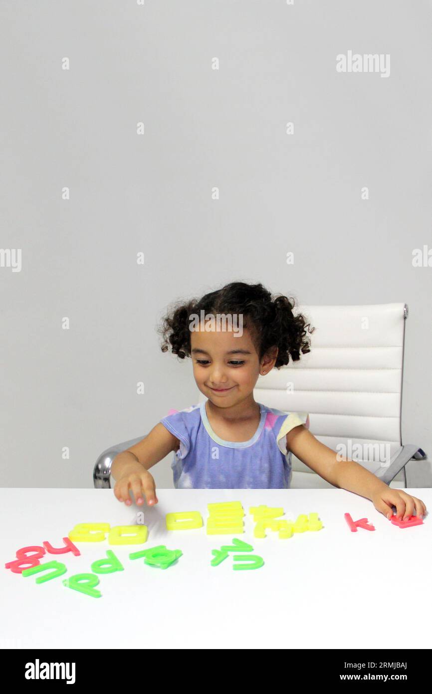 3-year-old brunette Latina girl plays with toy letters and numbers to ...