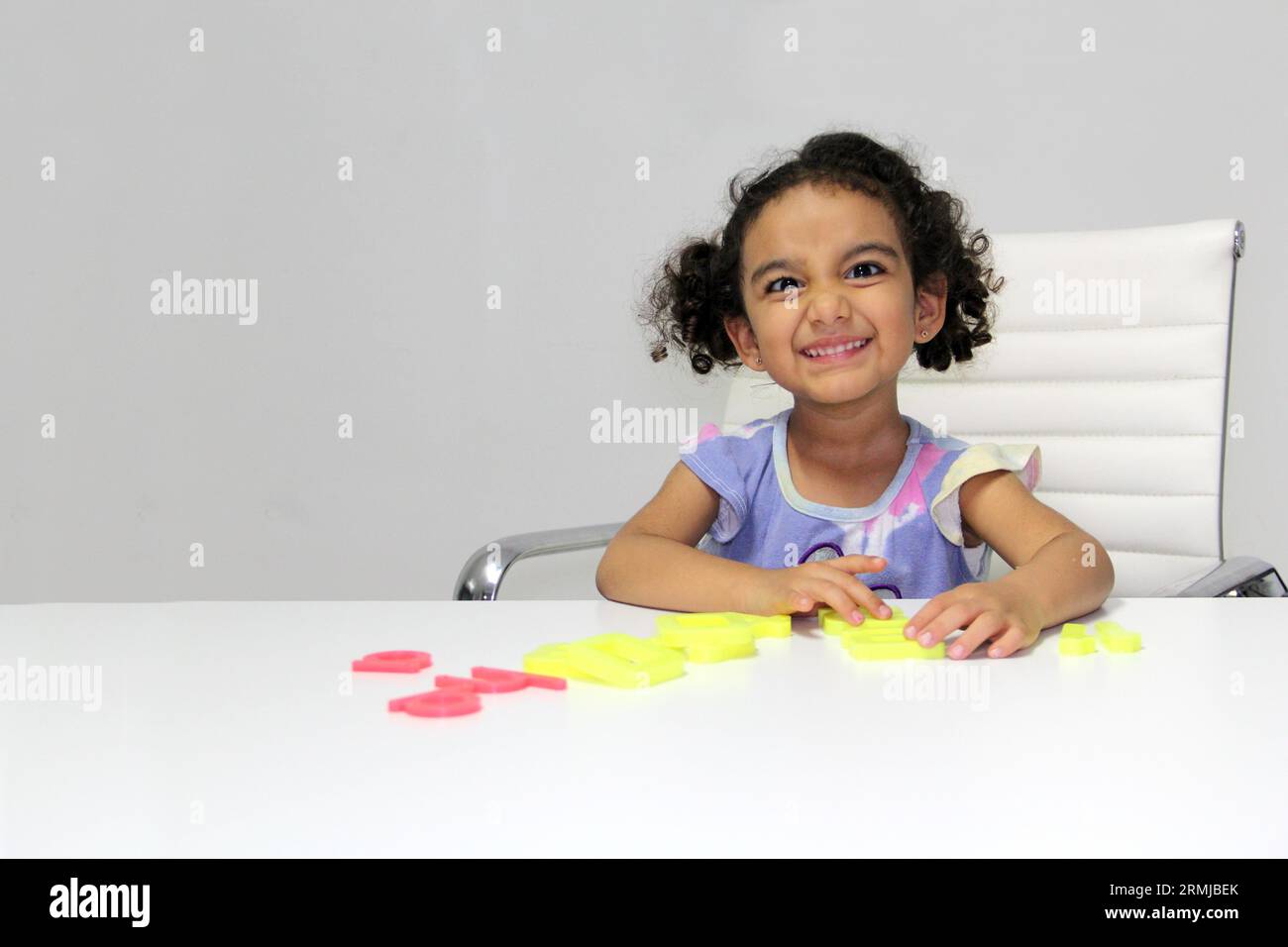 3-year-old brunette Latina girl plays with toy letters and numbers to ...