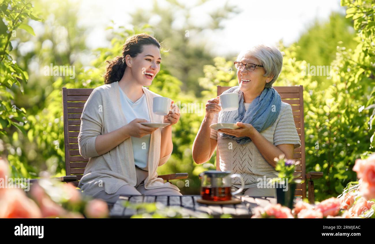 Happy young woman and her mother drinking tea in summer morning. Family ...