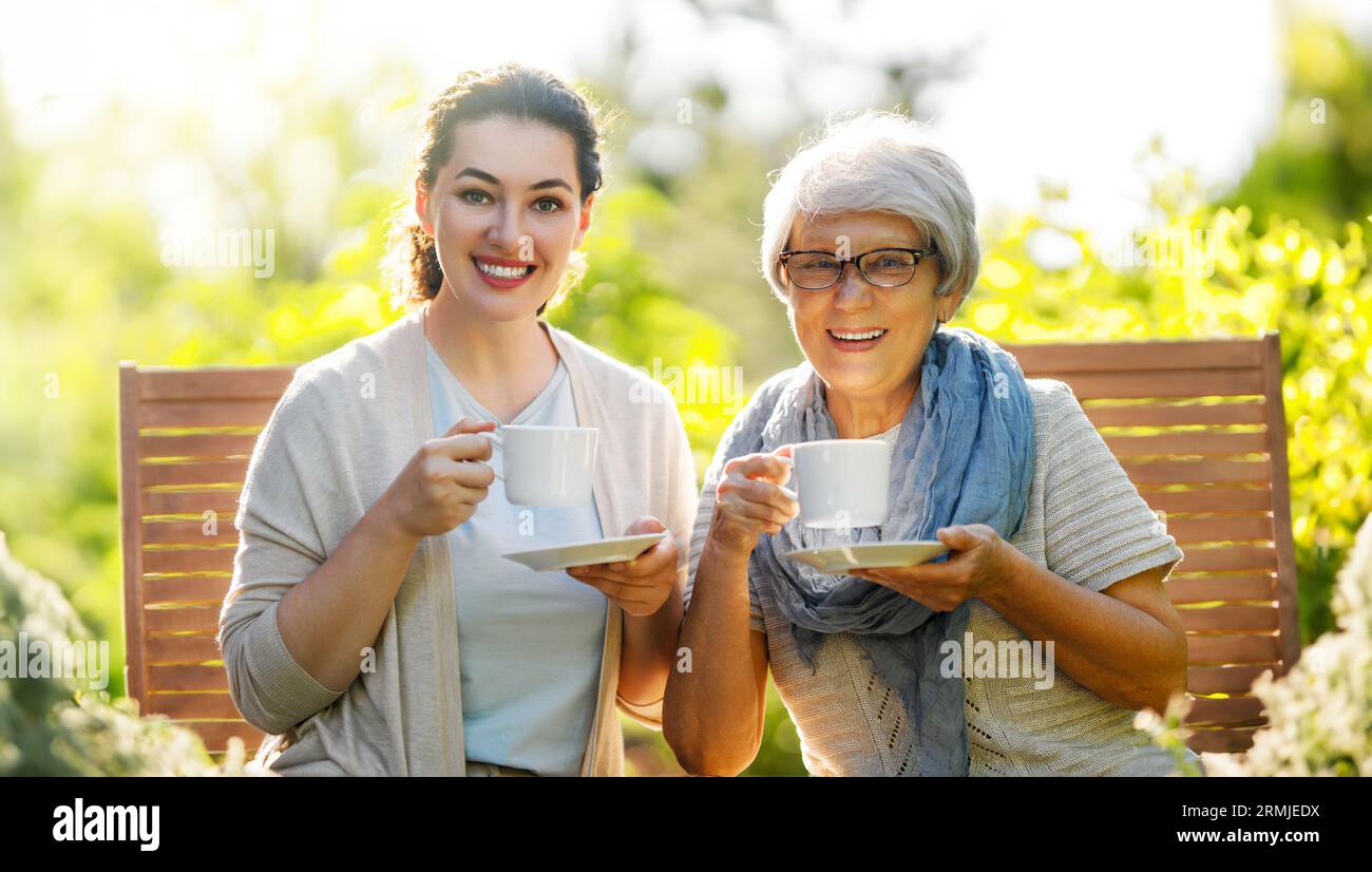 Happy young woman and her mother drinking tea in summer morning. Family ...