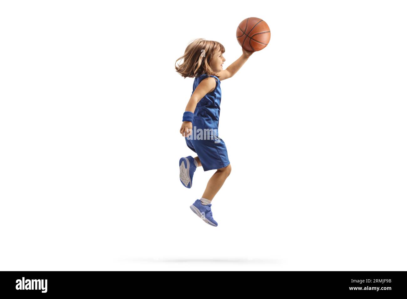 Girl in a blue sports jersey holding a basketball and jumping isolated ...