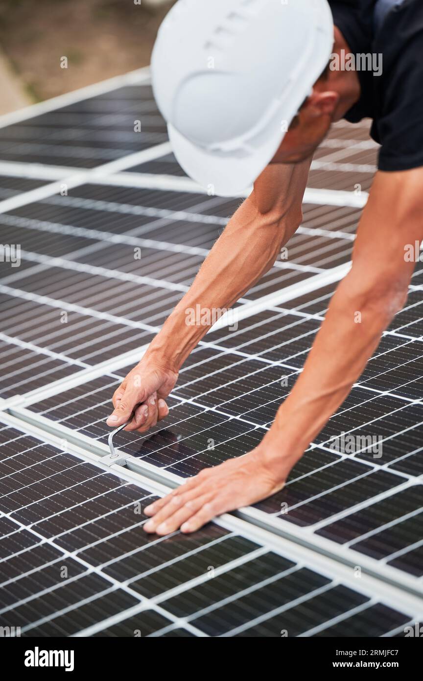 Man installer mounting photovoltaic solar moduls on roof of house ...