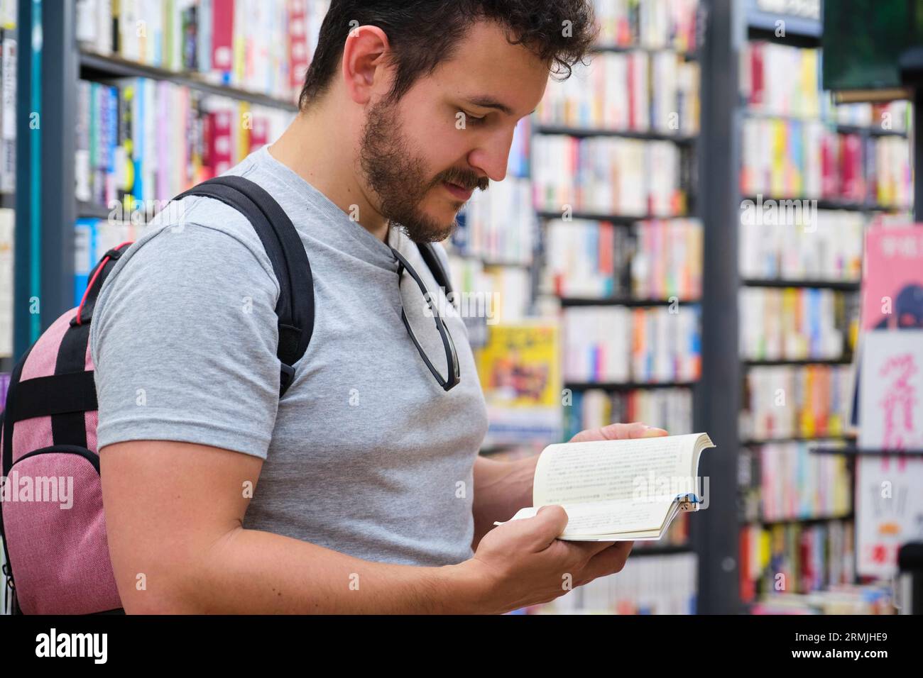 Latin tourist reading a comic at a Japanese comic book store in Tokyo ...