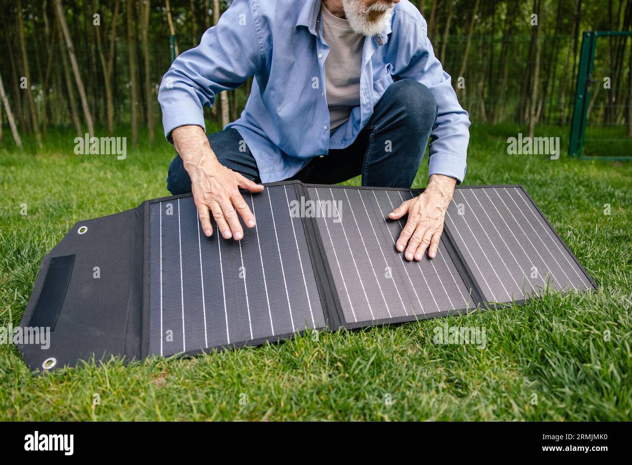 Senior man holding solar panel on in green yard Stock Photo - Alamy