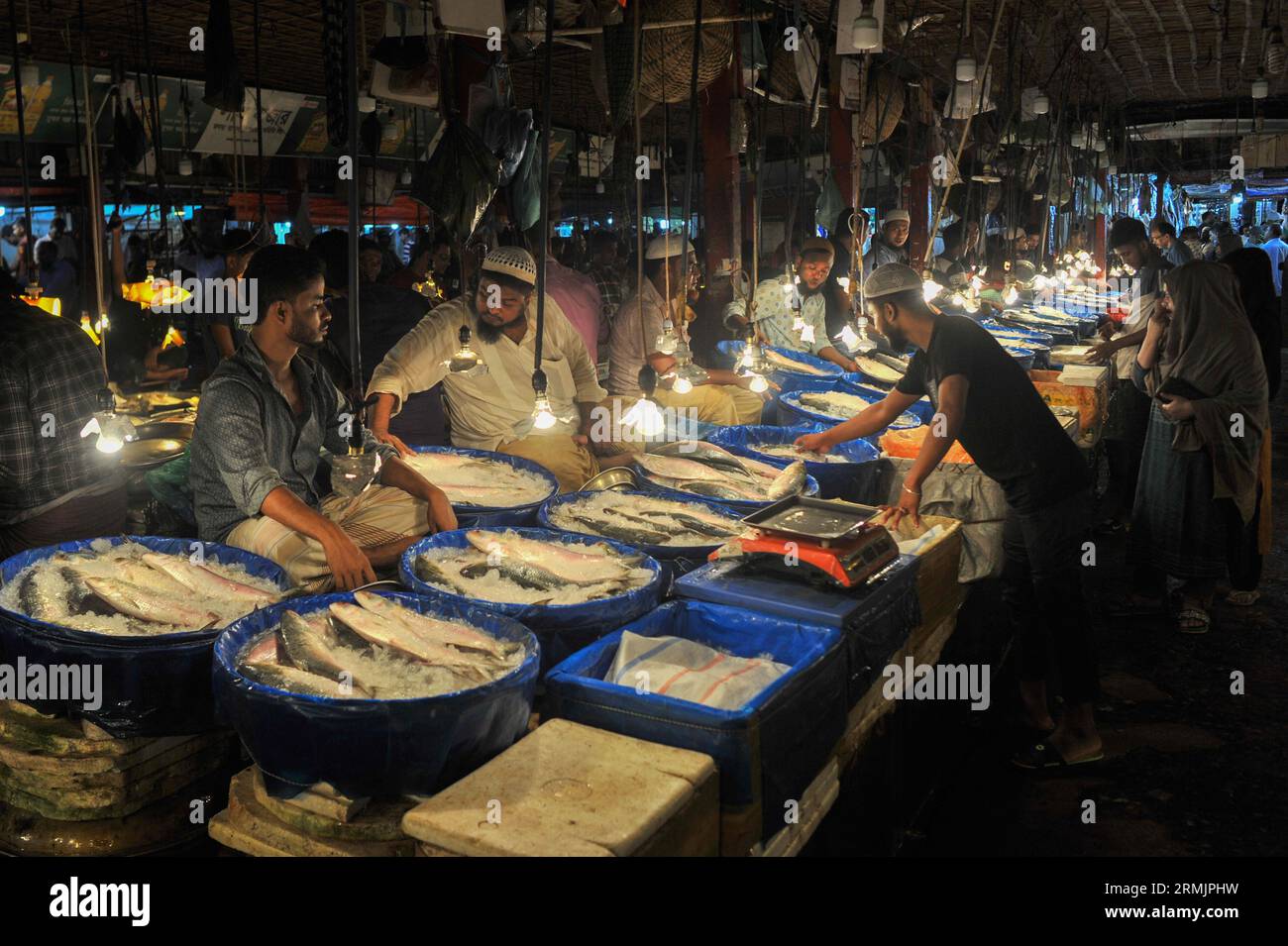People buy Hilsa fish at the Lalbazar fish market in Sylhet city ...