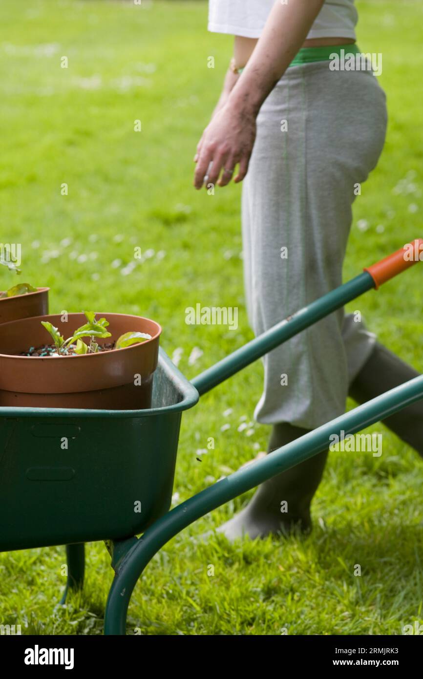 Young woman standing next to wheelbarrow gardening Stock Photo - Alamy