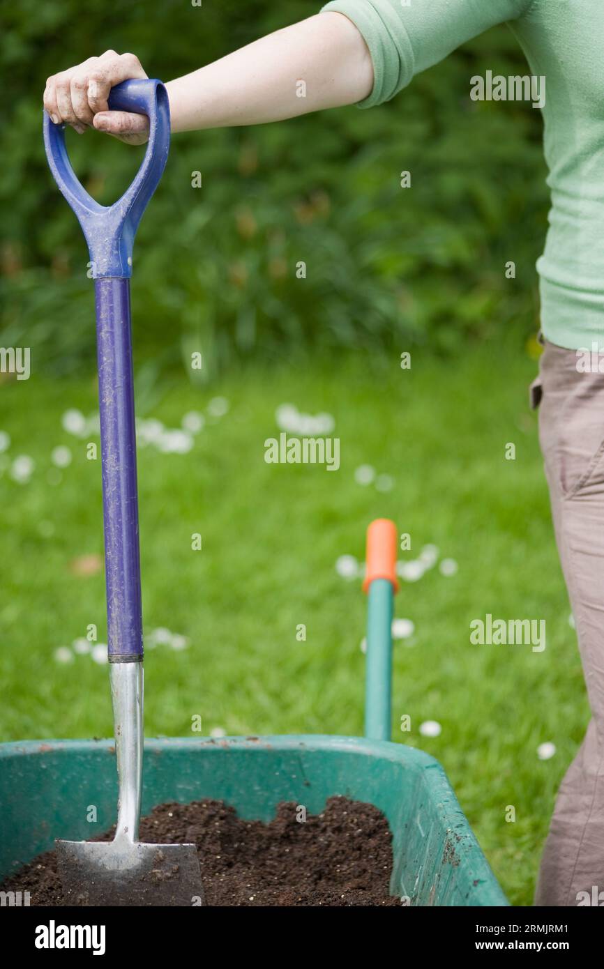 Young woman standing next to wheelbarrow with garden spade Stock Photo ...