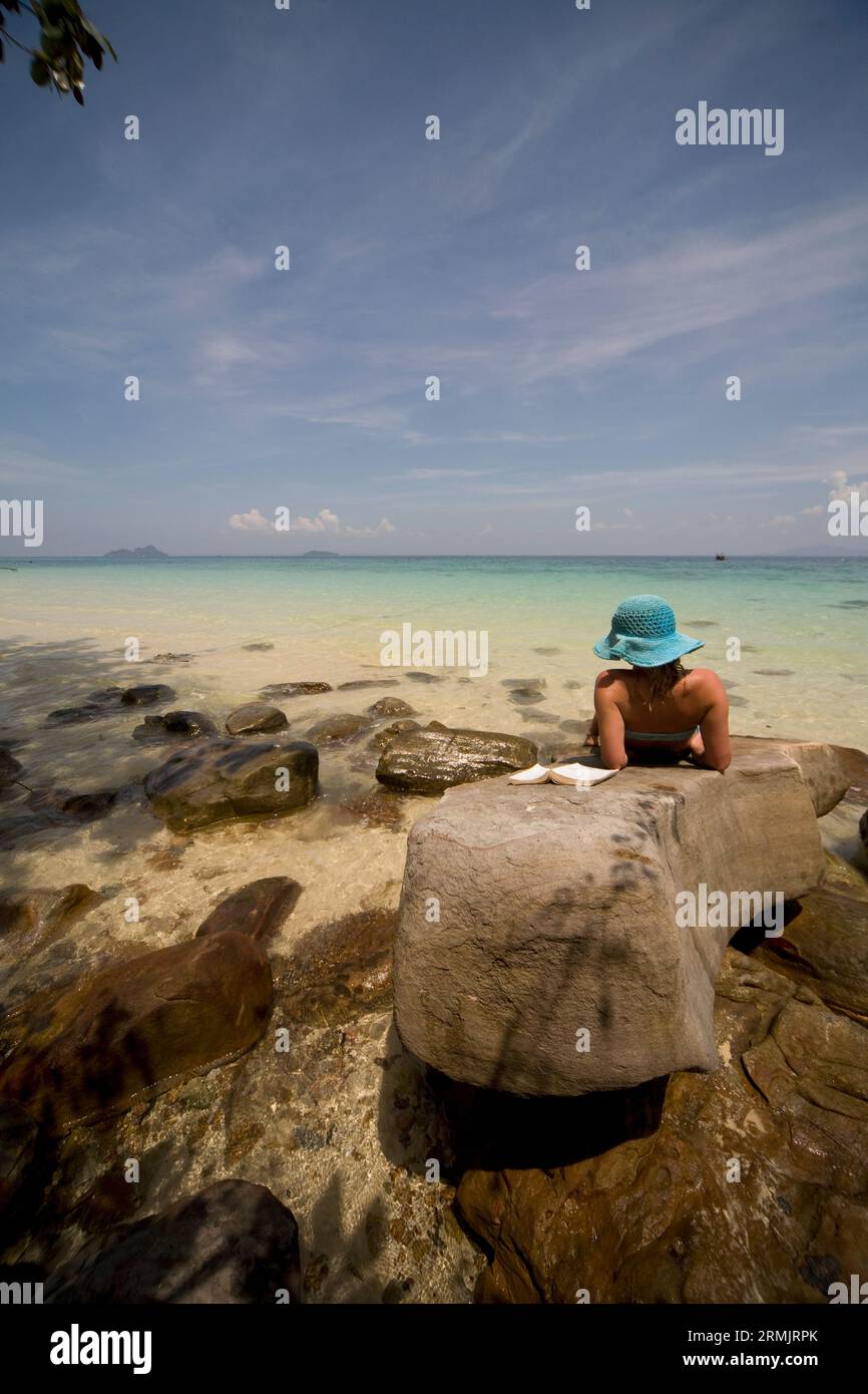 Young woman lying on rocks sunbathing and relaxing, Koh Phi Phi ...