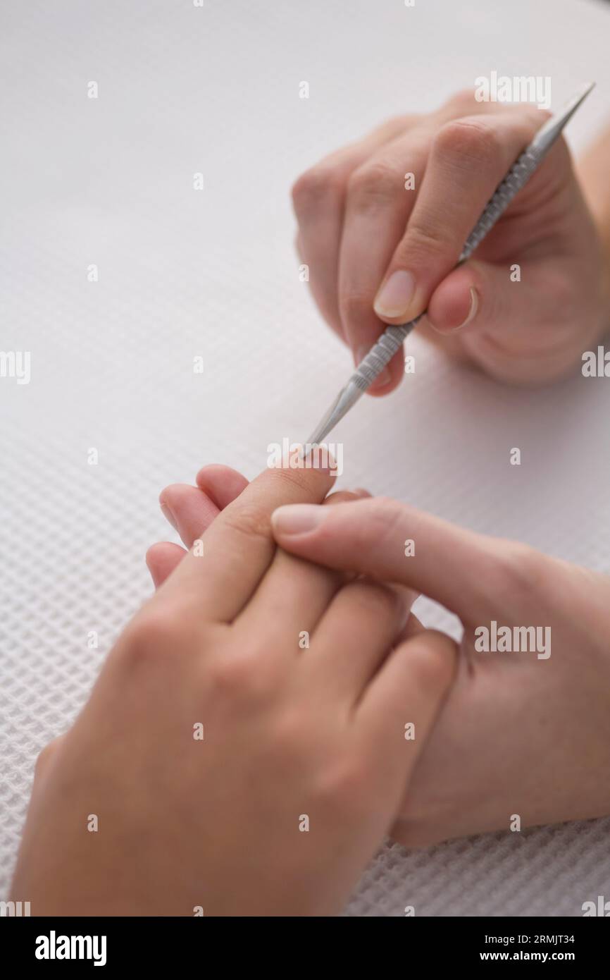 Close up of manicurist's hand pushing woman's cuticles with cuticle ...