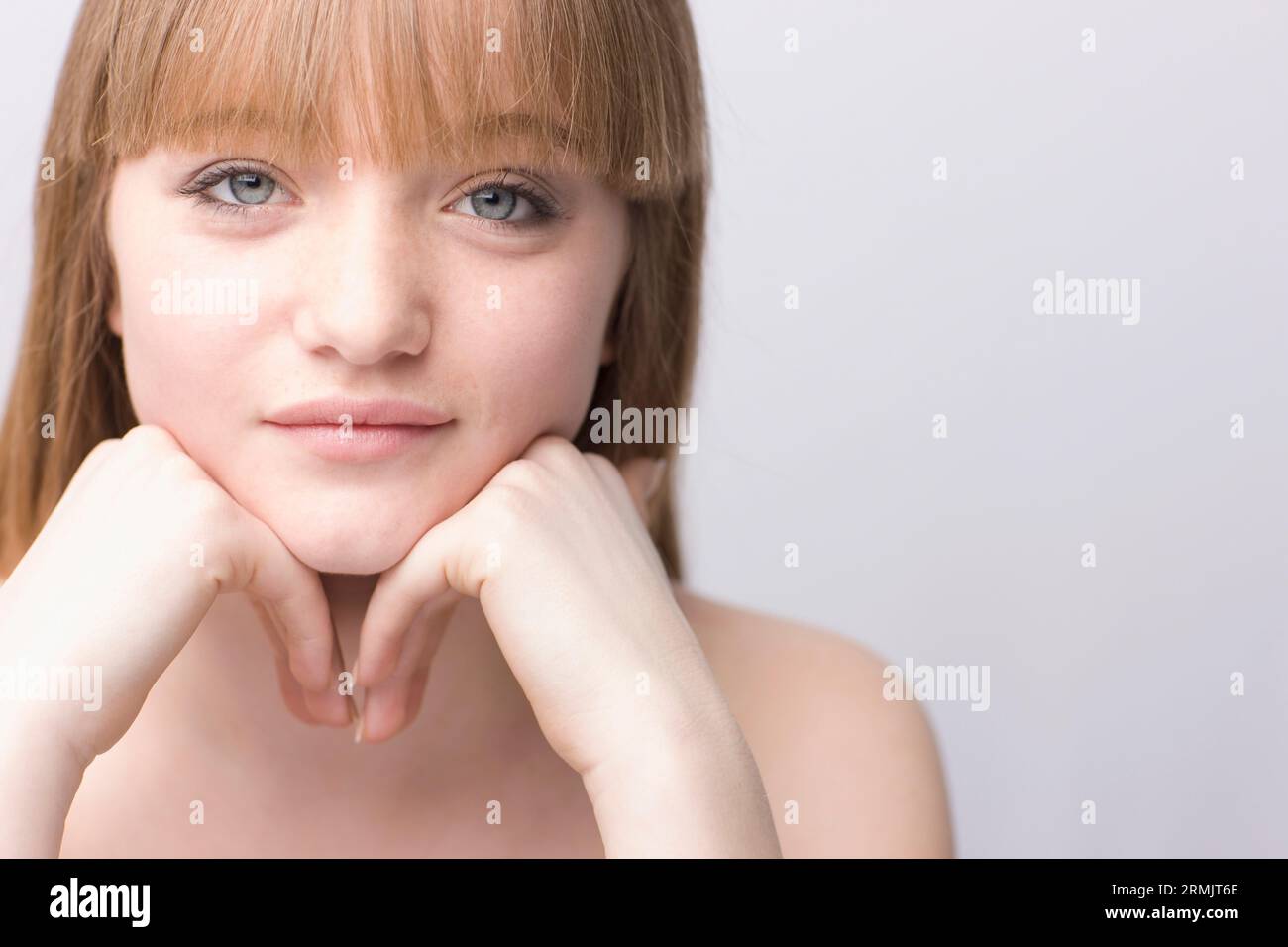 Young woman with hands on chin smiling Stock Photo - Alamy